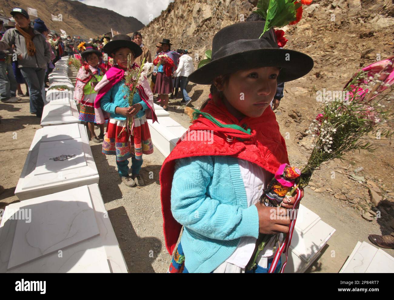 Girls stand amidst coffins during burial ceremonies for victims of a ...