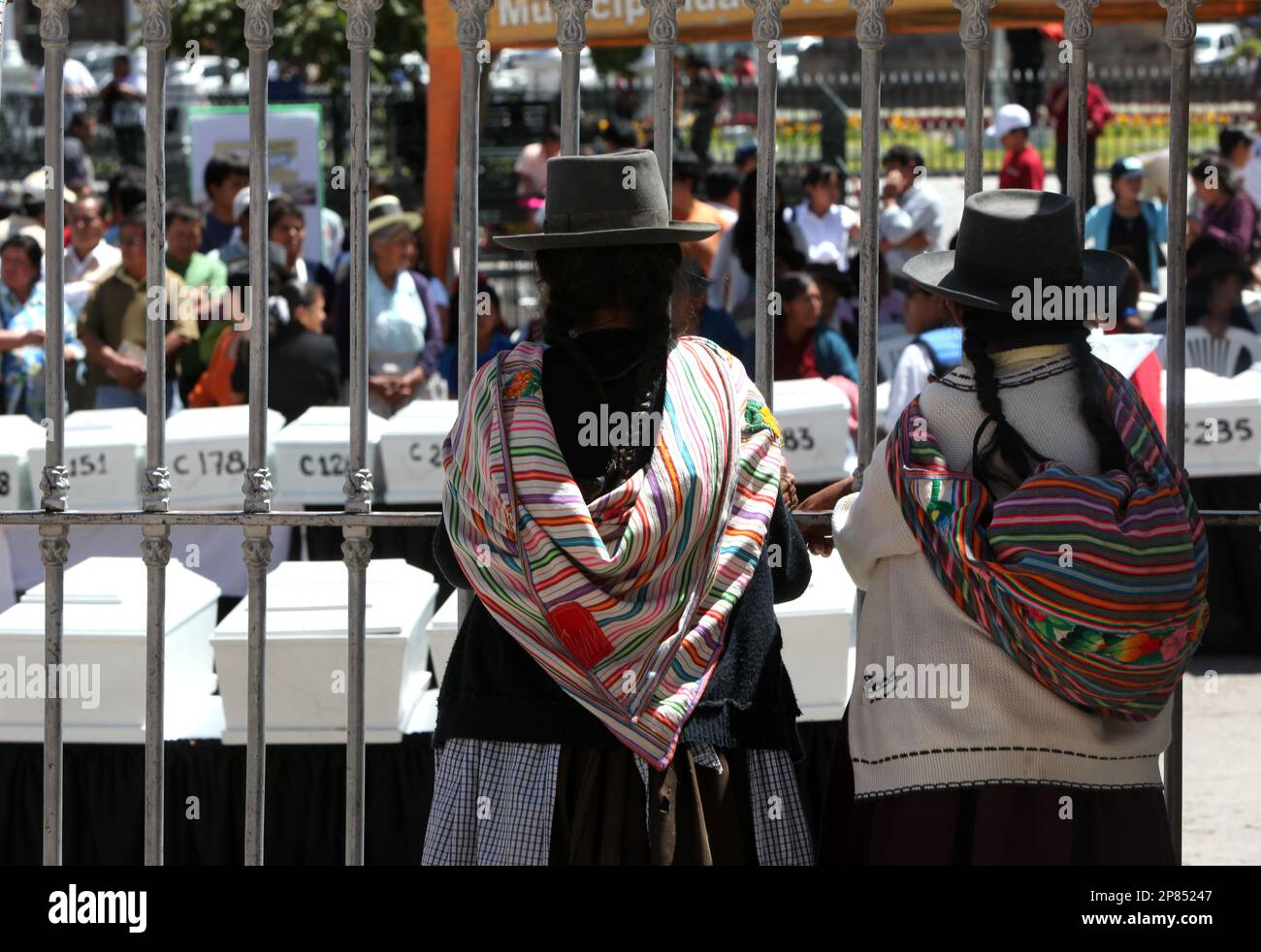 Two women, look at a line of coffins containing remains of people ...