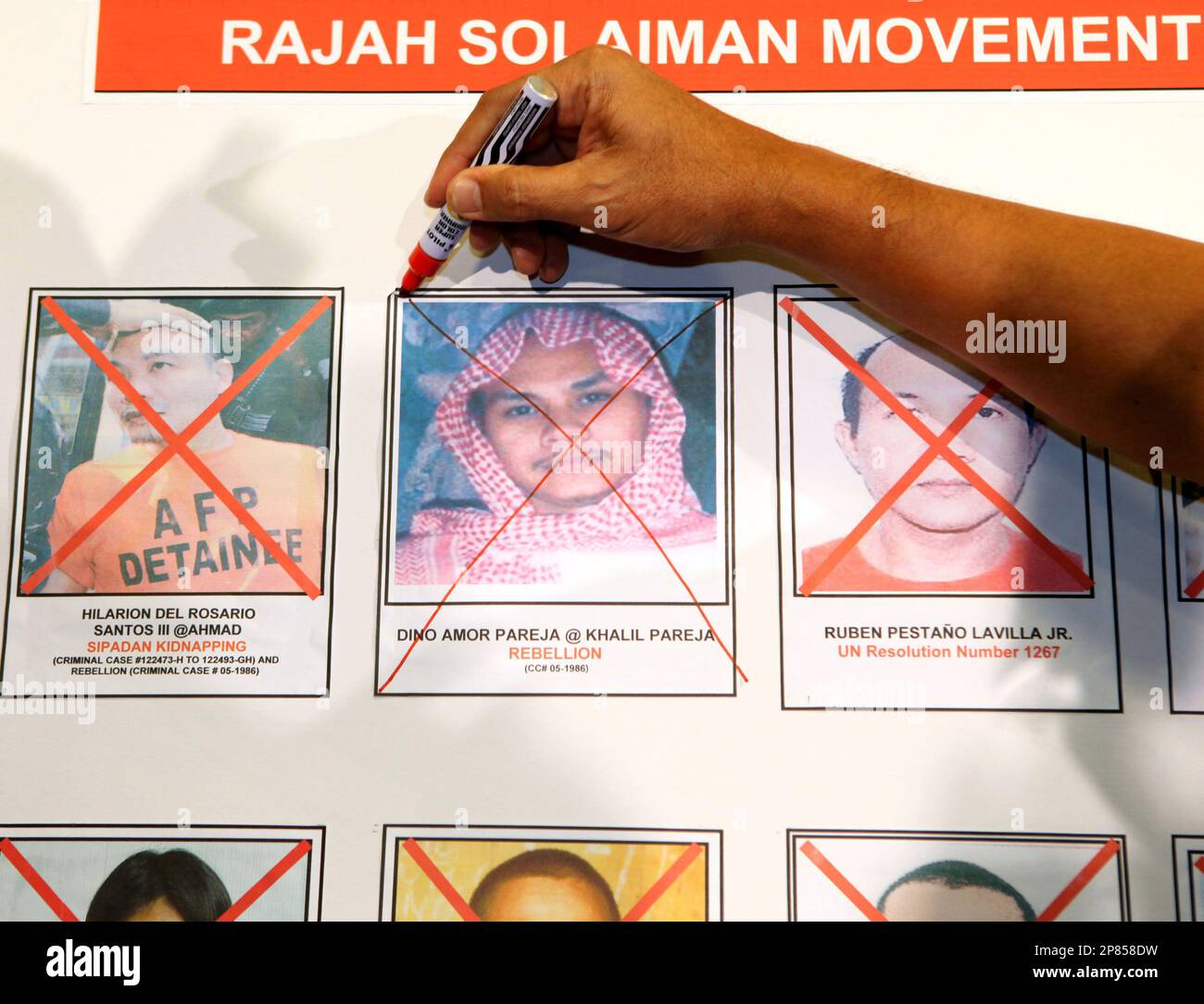 Philippine National Police Chief Jesus Versoza crosses out the wanted poster showing Dino Amor ...