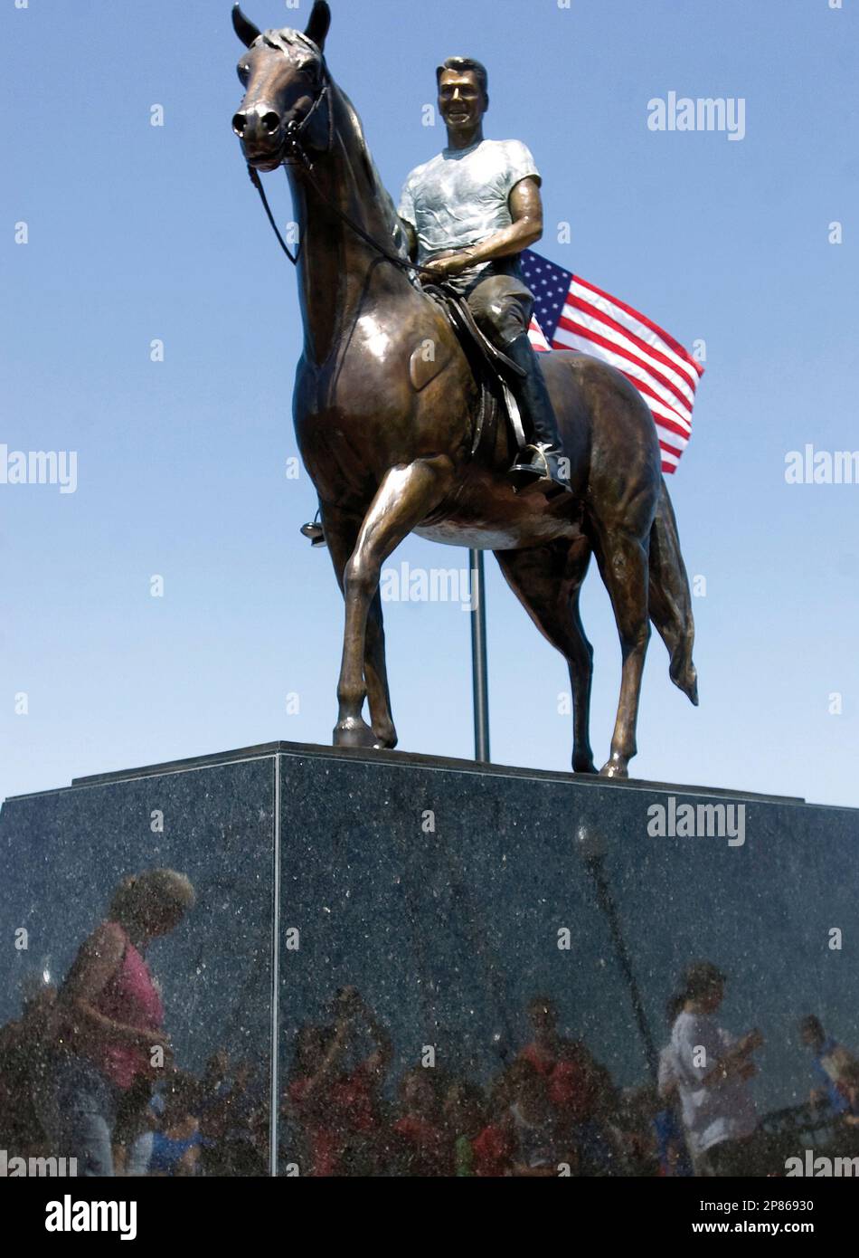 Visitors to a riverfront dedication are reflected in the marble base of ...