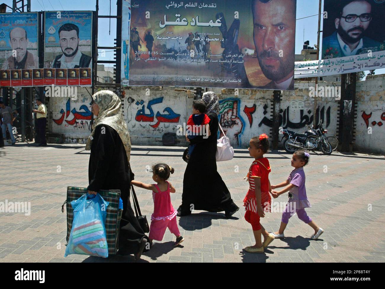 Palestinians walks past a billboard, center, advertising the film "Emad ...