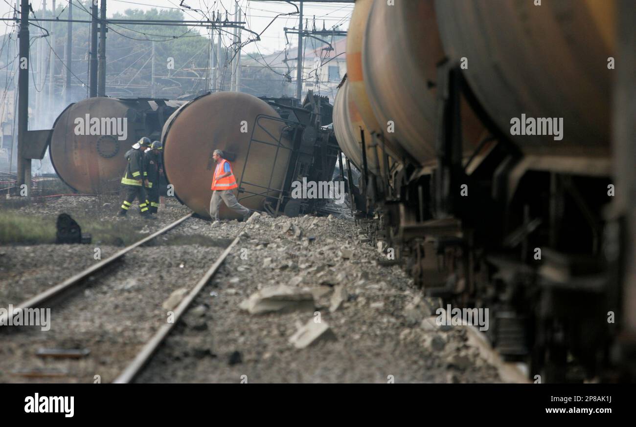 Italian firefighters walk past the burned cars of a freight train in ...