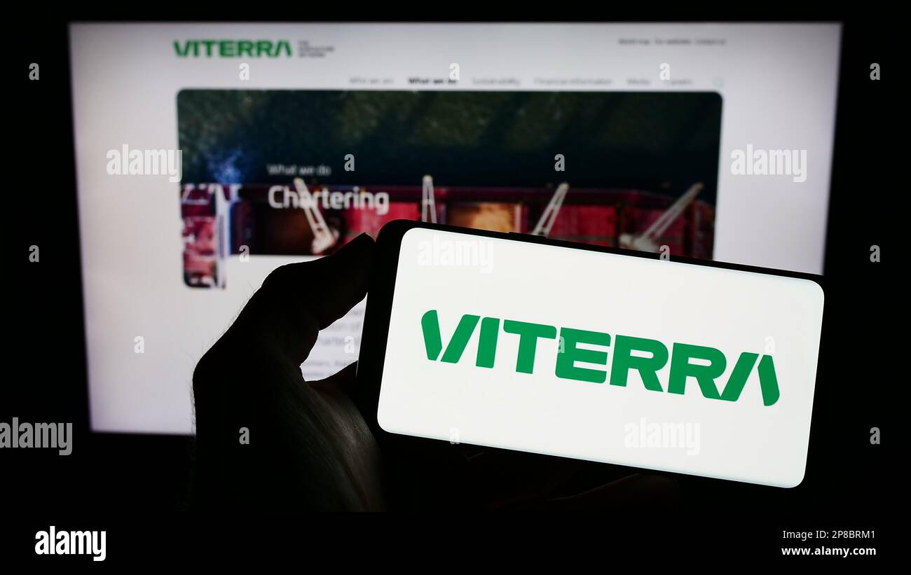 Person, die ein Mobiltelefon mit dem Logo des Handelsunternehmens ...