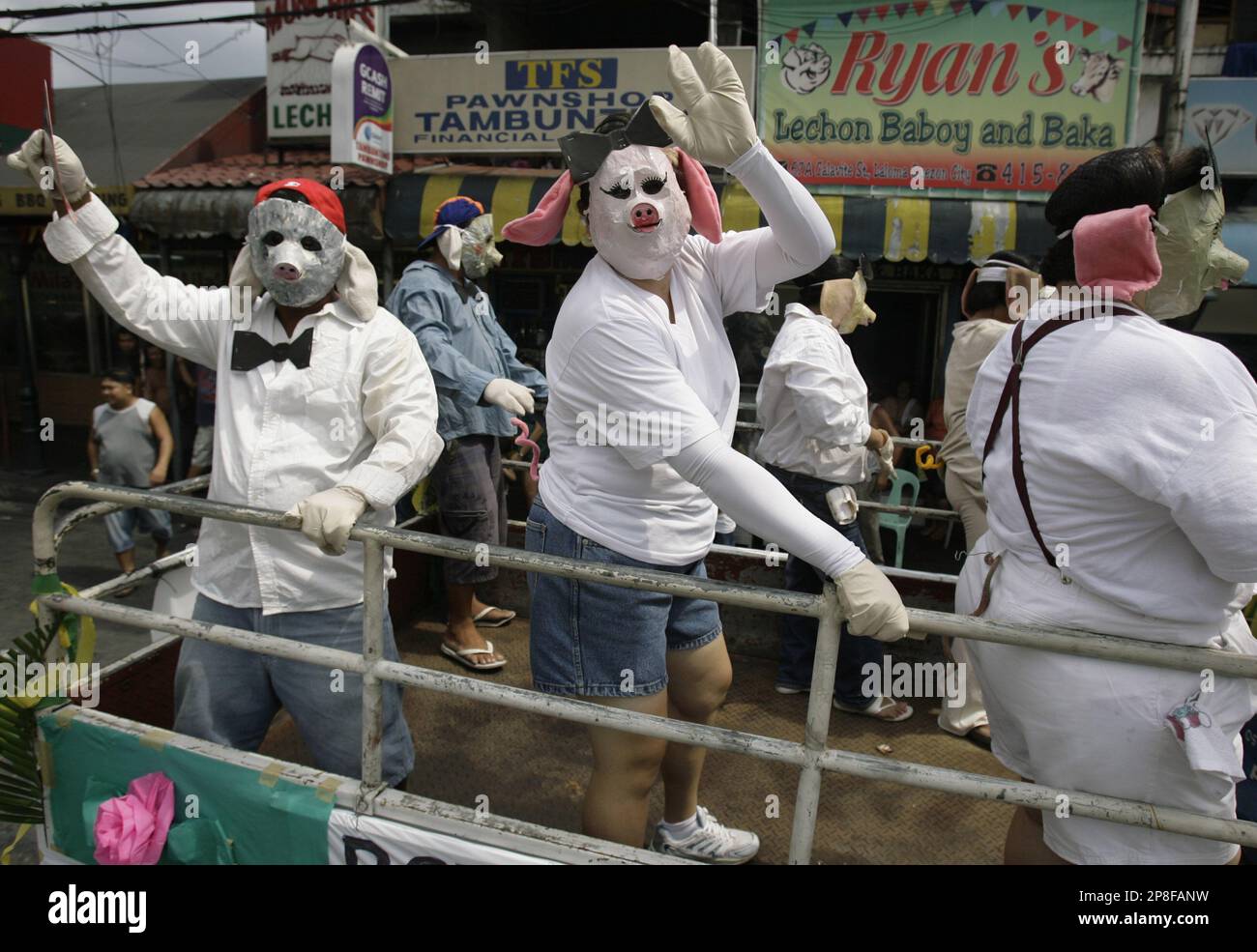 Filipinos wearing masks of pigs parade during a town fiesta in La Loma ...