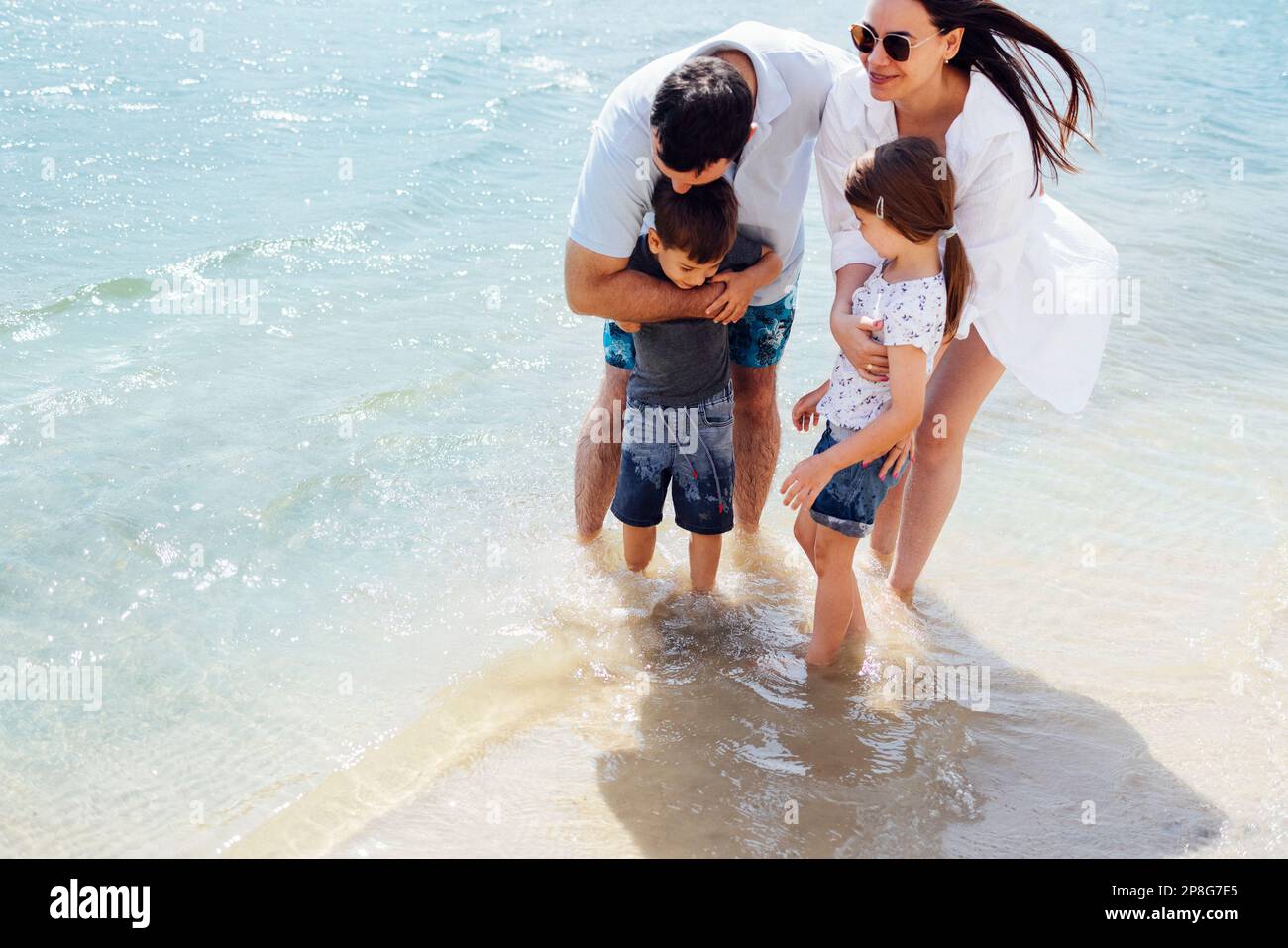 Glückliche Familie auf dem See oder Fluss. Sohn und Tochter Rennen auf dem Wasser und spritzen ...