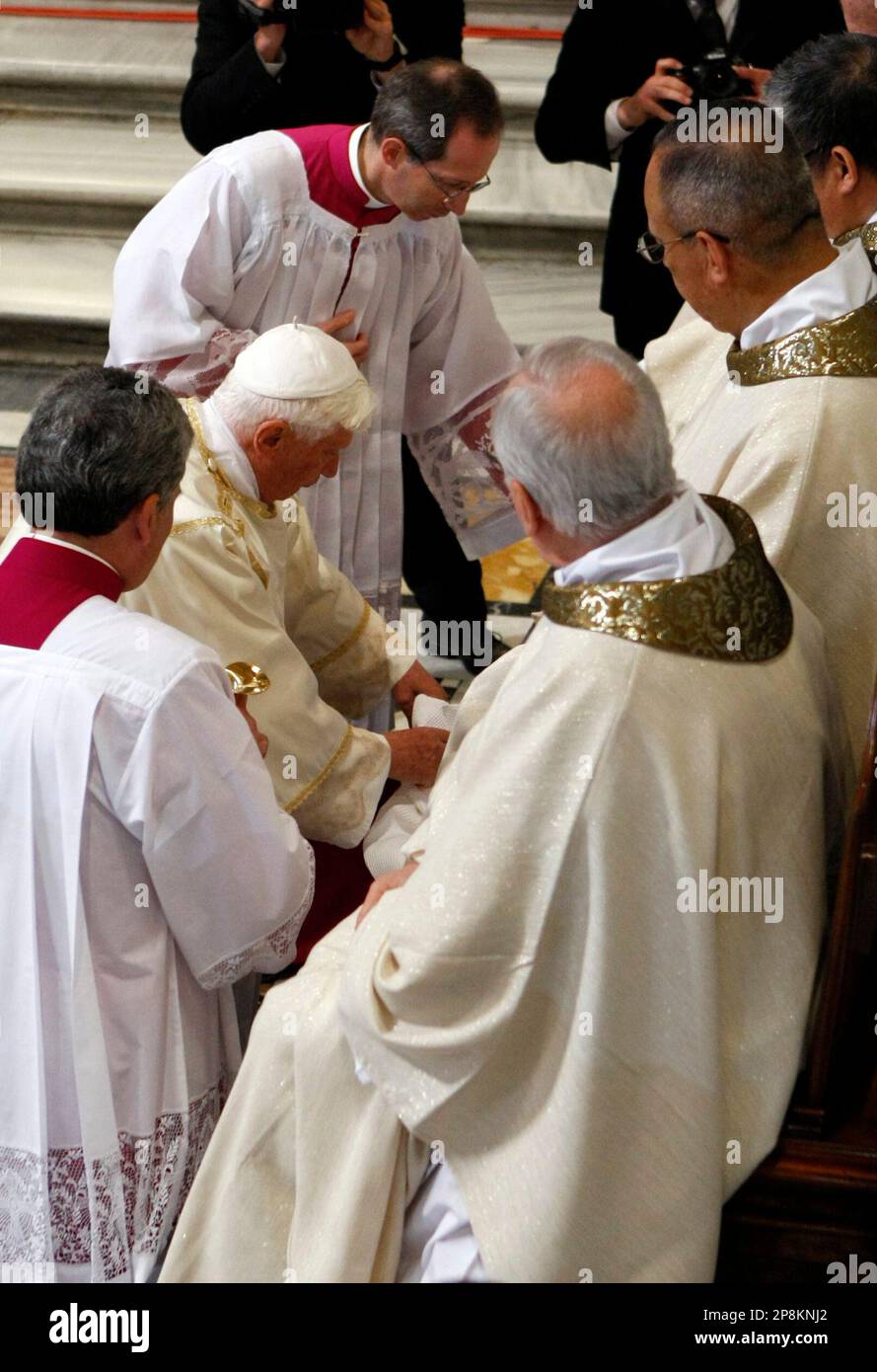 Pope Benedict XVI, at left wearing white cap, washes the foot of an ...