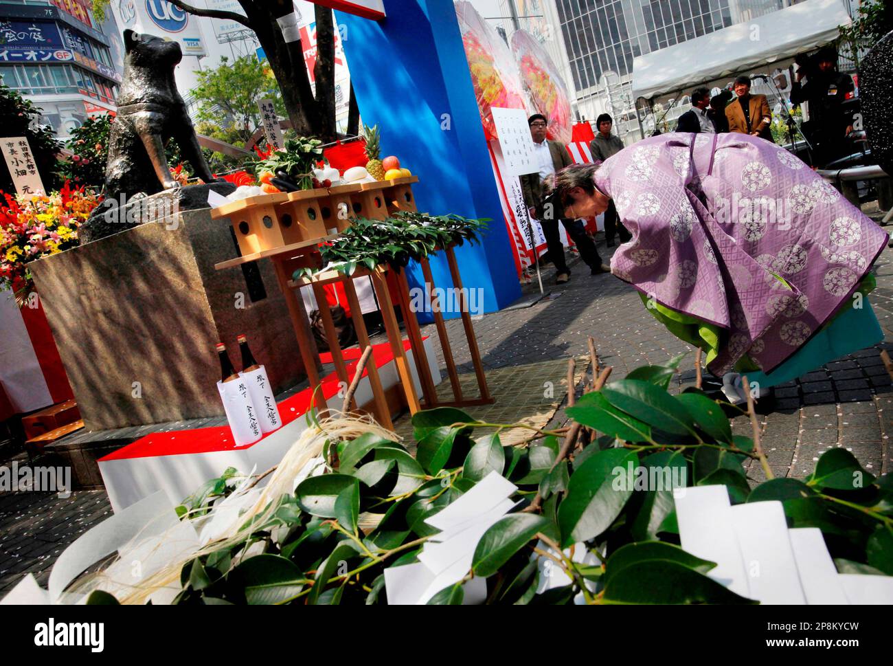A shinto priest offers prayers in front of a bronze statue of Japanese ...