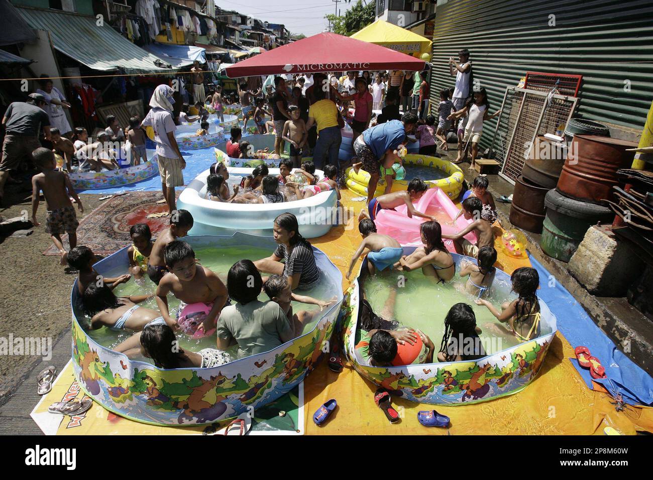 Filipinos living at a slum area dip themselves in plastic pools during ...