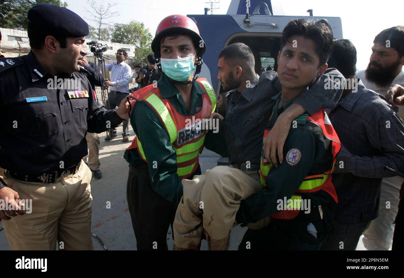 Rescuers carry an injured Pakistani police officer outside a police ...