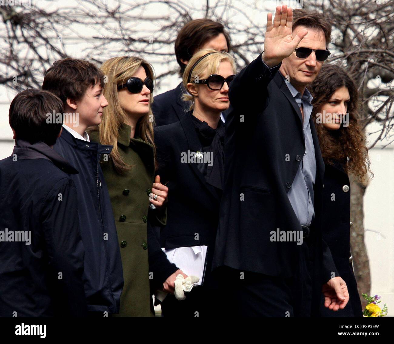 Liam Neeson waves to journalists as he arrives with family, from left ...
