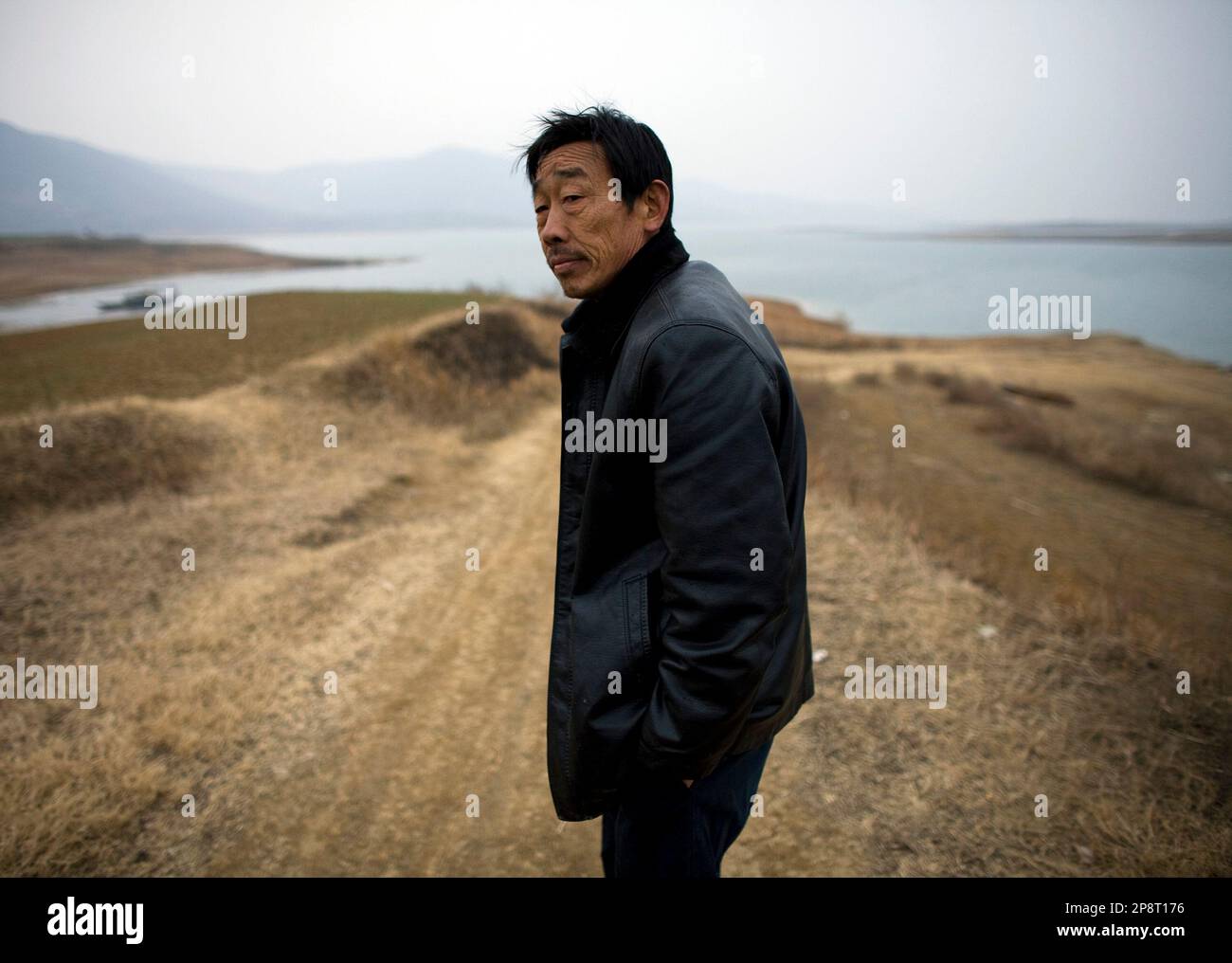 Zhang Jiqing, a farmer, walks near the lake at Zhangyigang village in ...