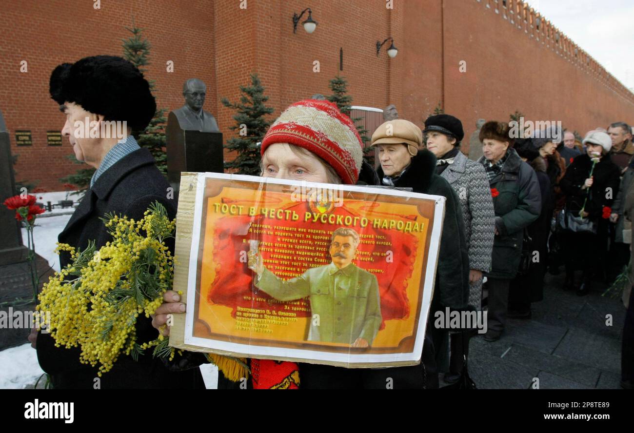 A woman holds a poster with Stalin's portrait as she and other Russian ...