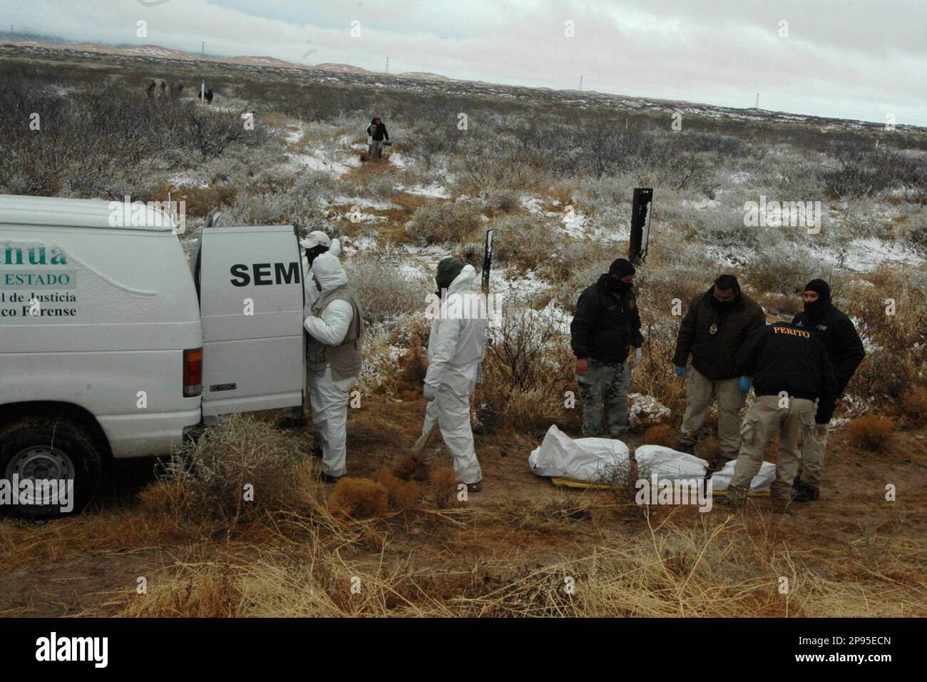 Police and forensic workers prepare to load bodies onto a truck after a ...