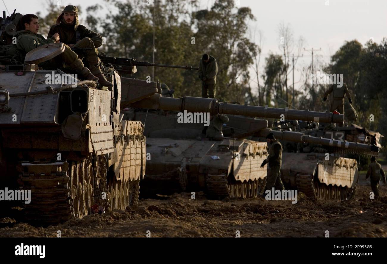 Israeli soldiers rest on top of a tank in position as they prepare to ...