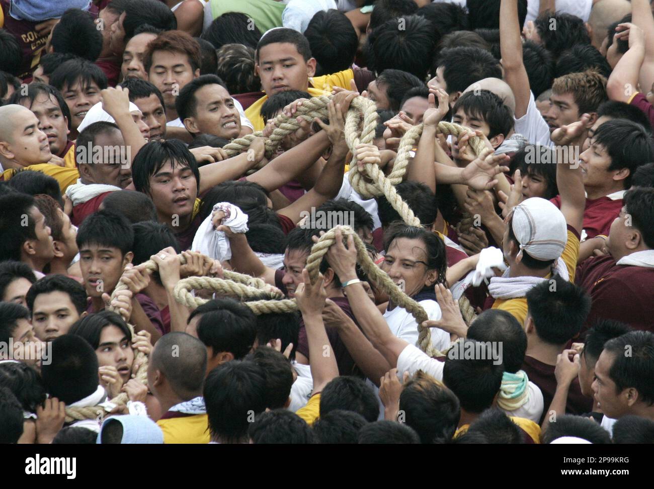Filipino barefoot devotees grab the rope which is tied to the carriage ...