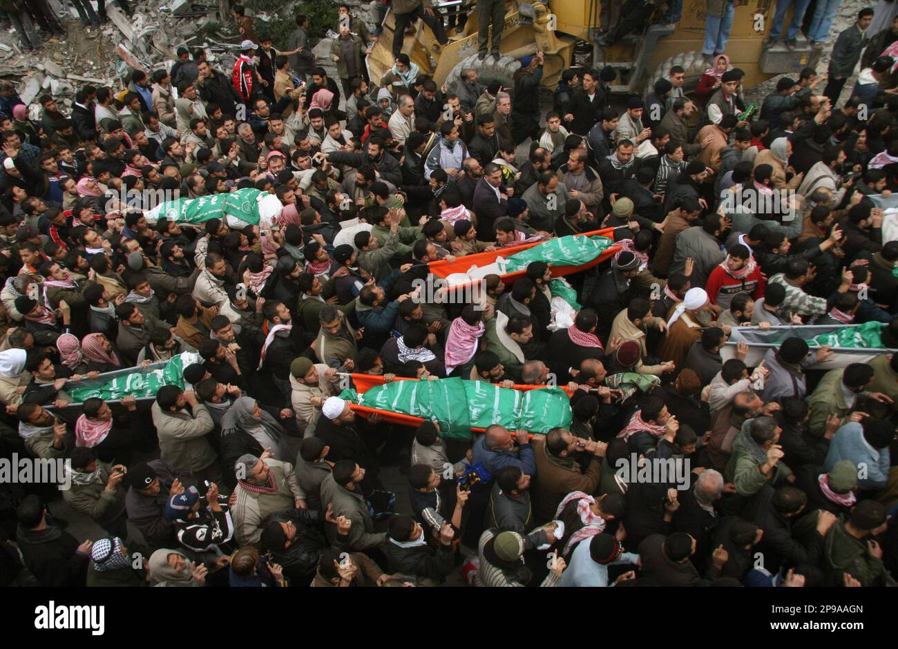 Palestinians carry six of fourteen bodies during the funeral procession ...