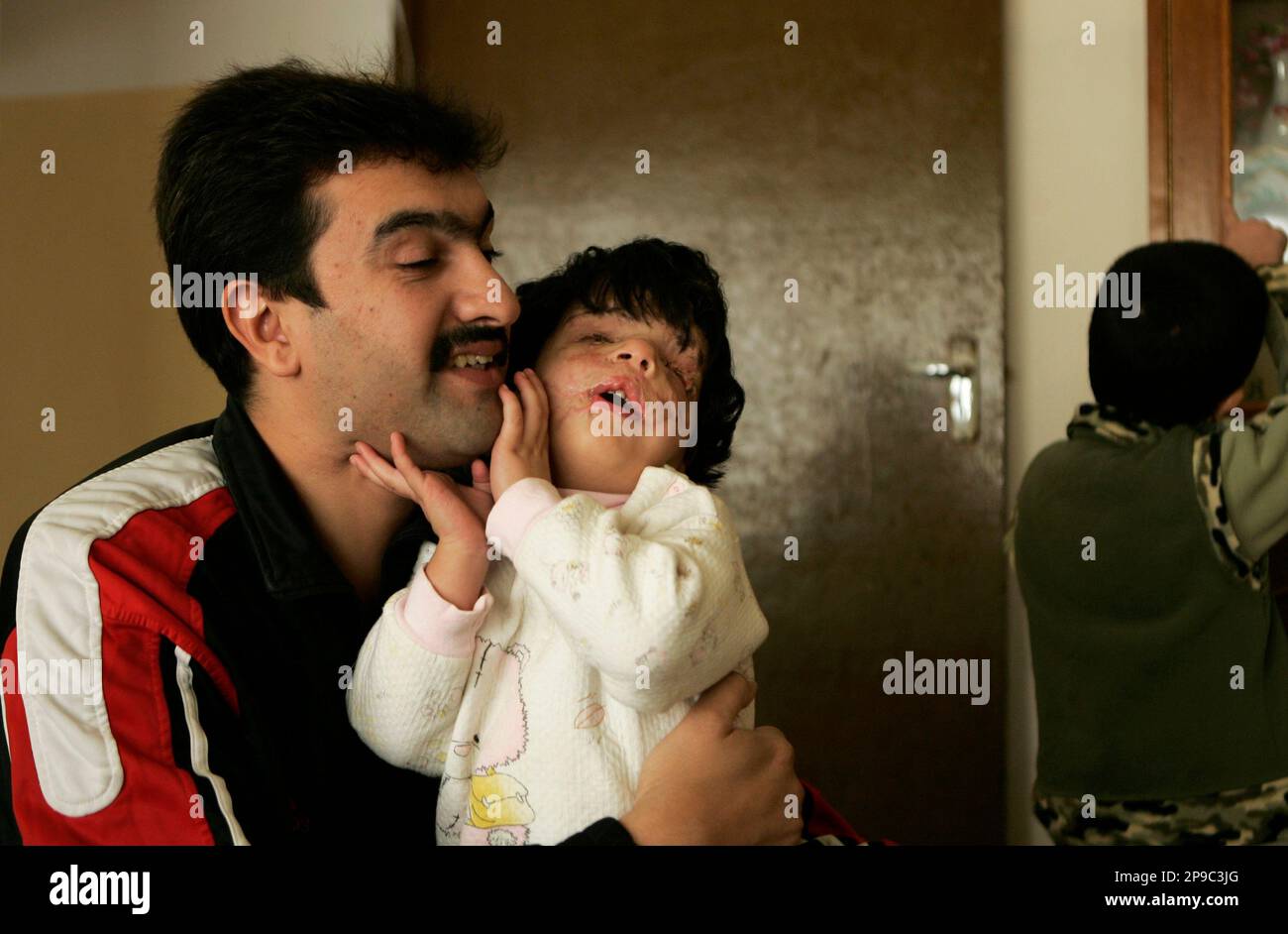 Husham Fadhil, 32, holds his 3-year-old daughter Shams, at their home ...