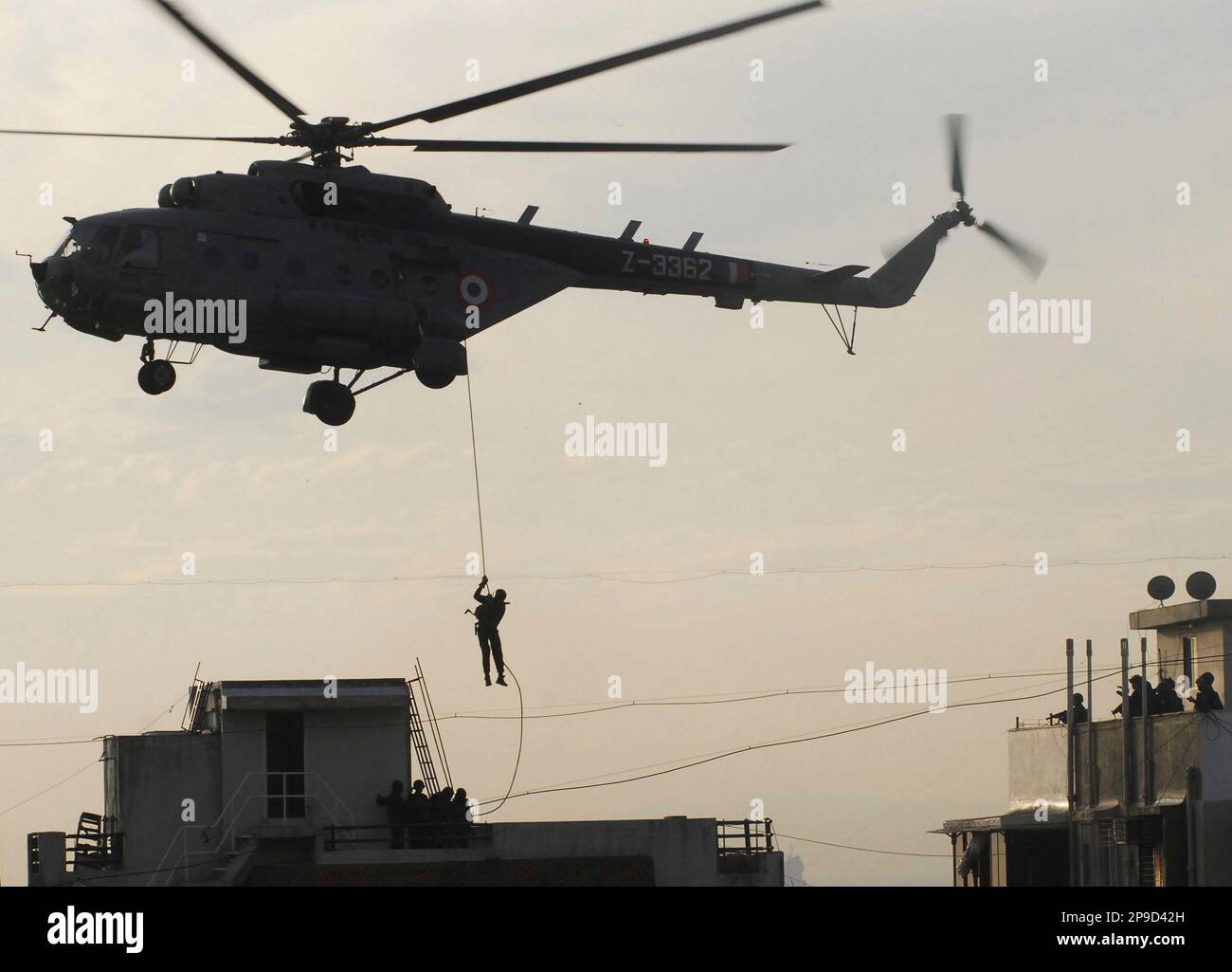 A National Security Guard commando comes down a rope to reach the top ...