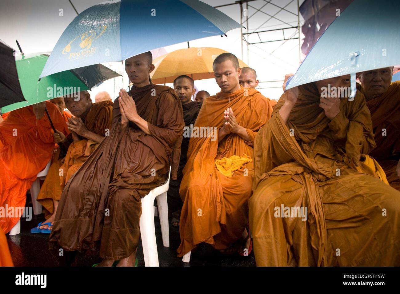 Buddhist monks are drenched during a thunderstorm as they perform a ...