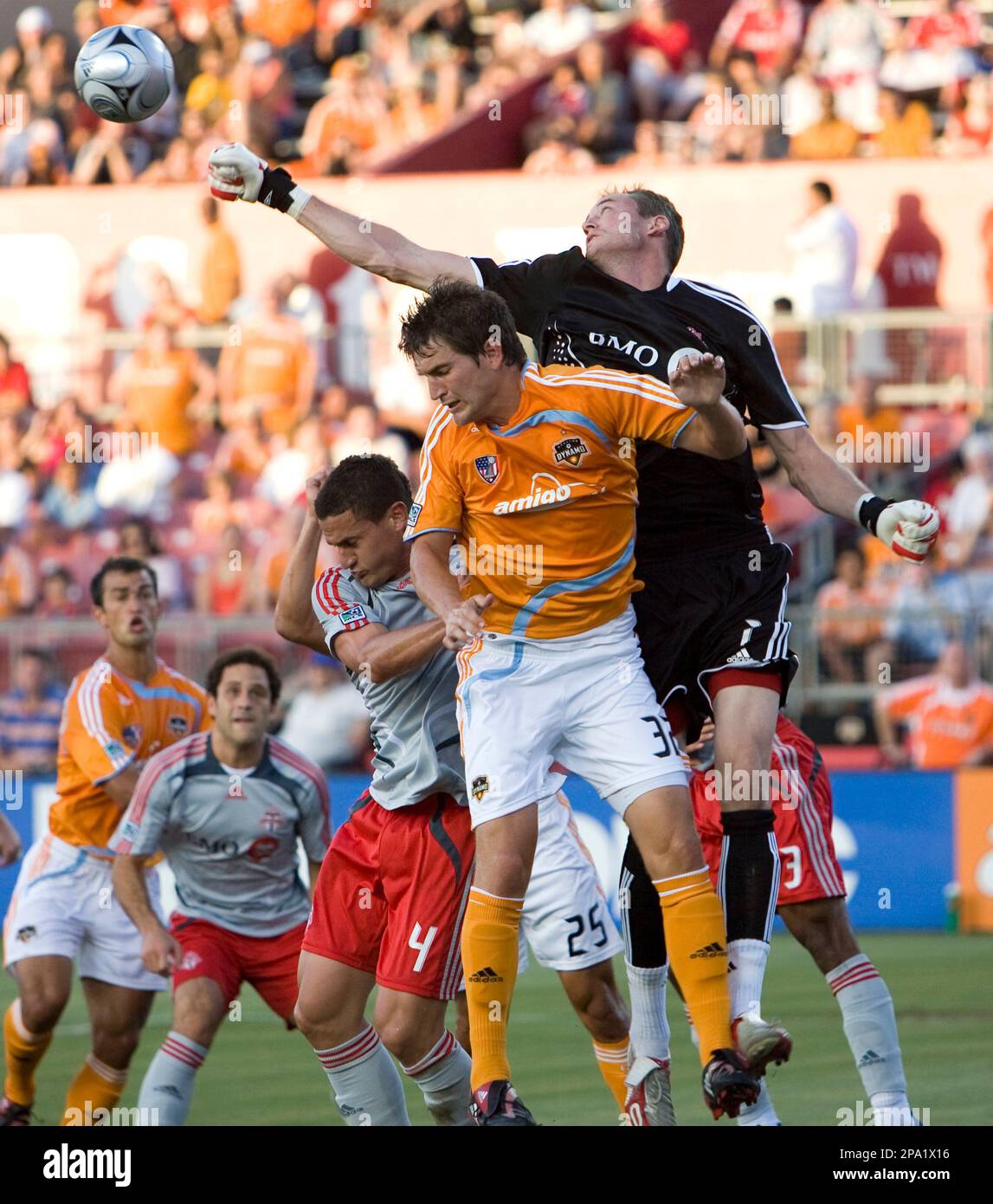 Toronto FC goalkeeper Greg Sutton, right, punches the ball away from ...