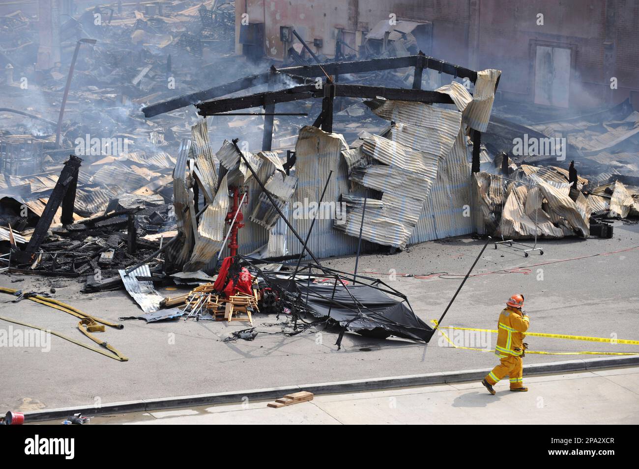 A firefighter walks past a destroyed studio lot from a fire at ...