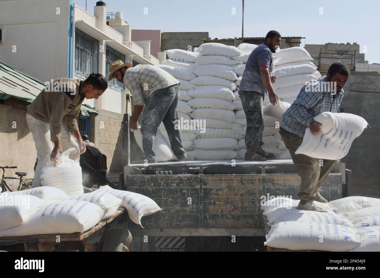 Palestinian unload a truck full of sacks of flour supplied by the UN ...