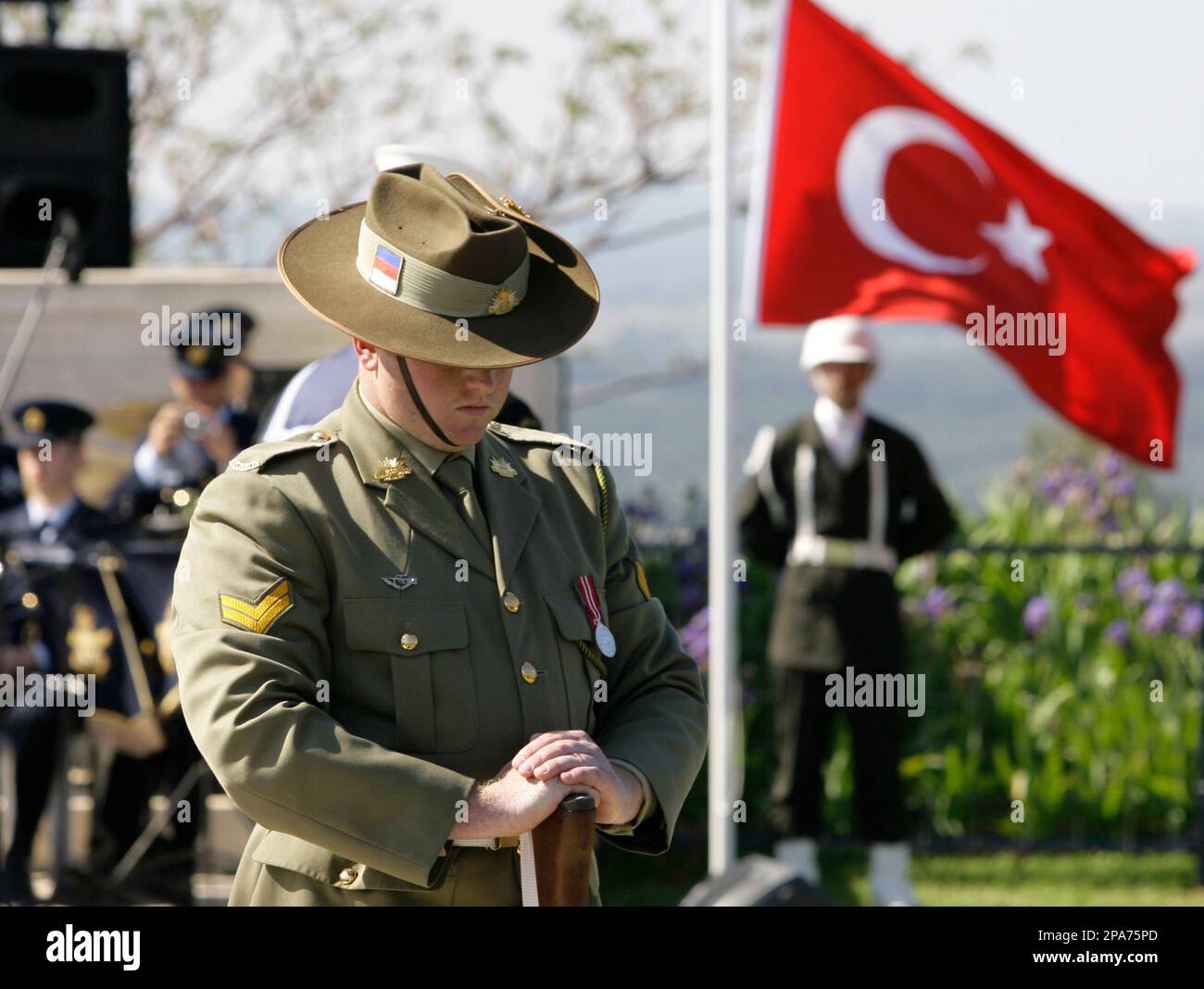 An Australian soldier, with a Turkish flag in the background, stands to ...