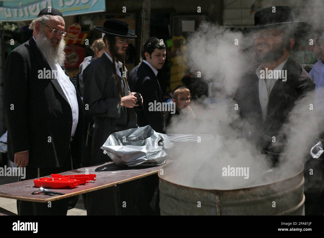 An ultra-Orthodox Jewish man dips silverware into boiling water to make ...