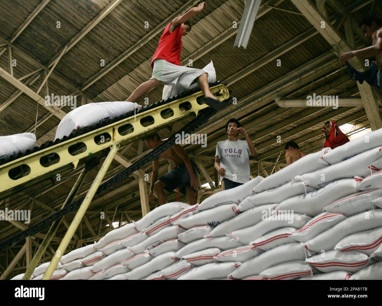 Workers stack imported rice which will be repacked and sold to poor ...
