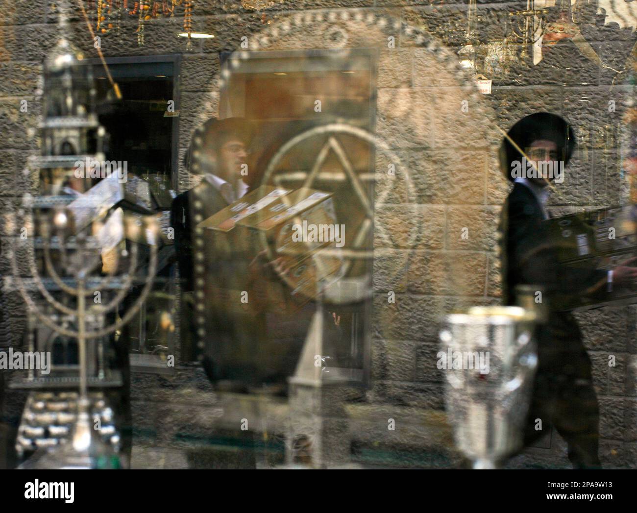 Ultra-orthodox Jewish men are reflected in a shop window displaying ...