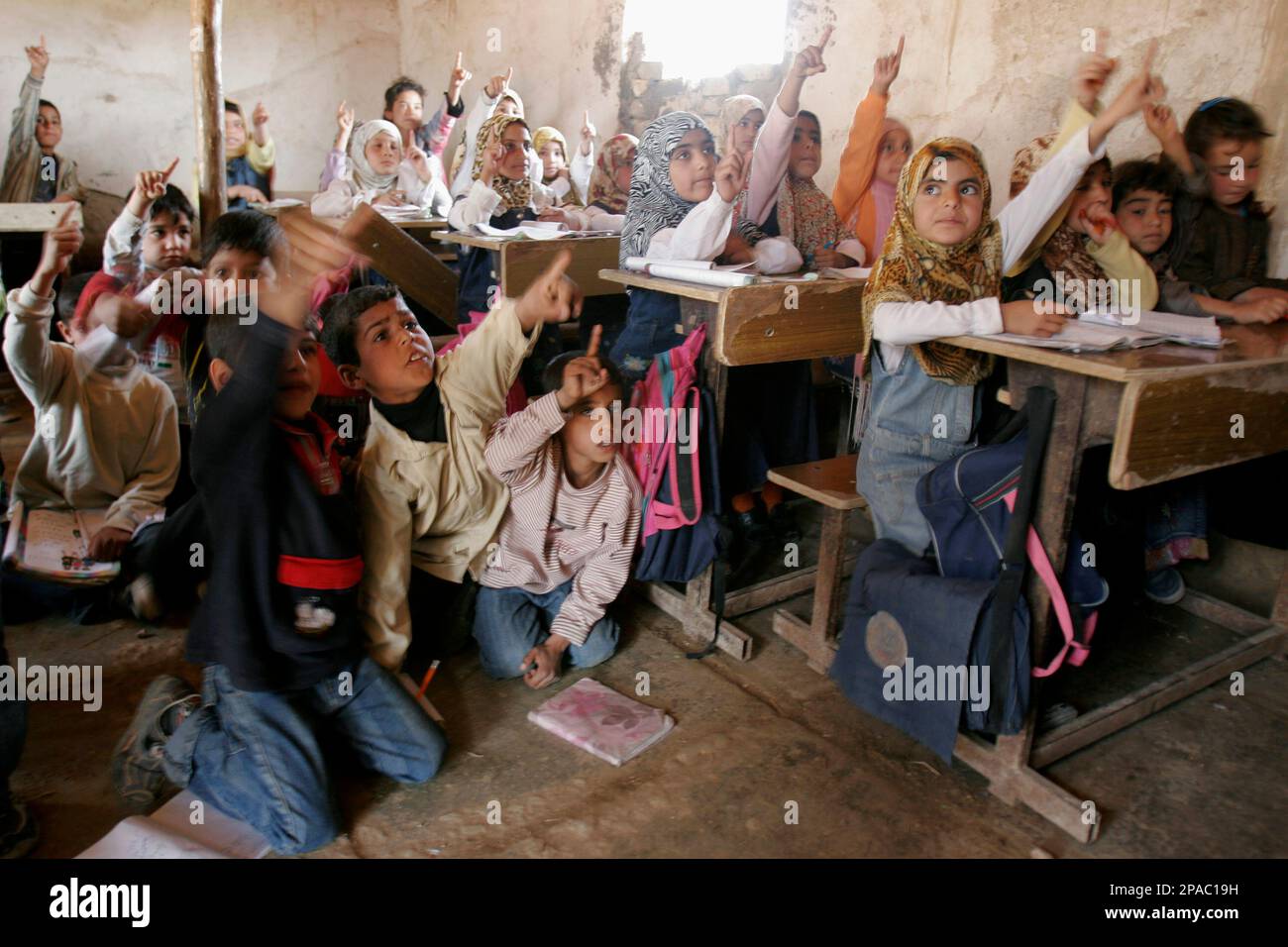 Iraqi children raise their hands as they attend a lesson at an ...