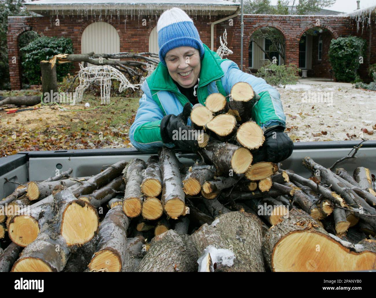Berniece McDonald loads wood cut from her downed tree at rear into her ...