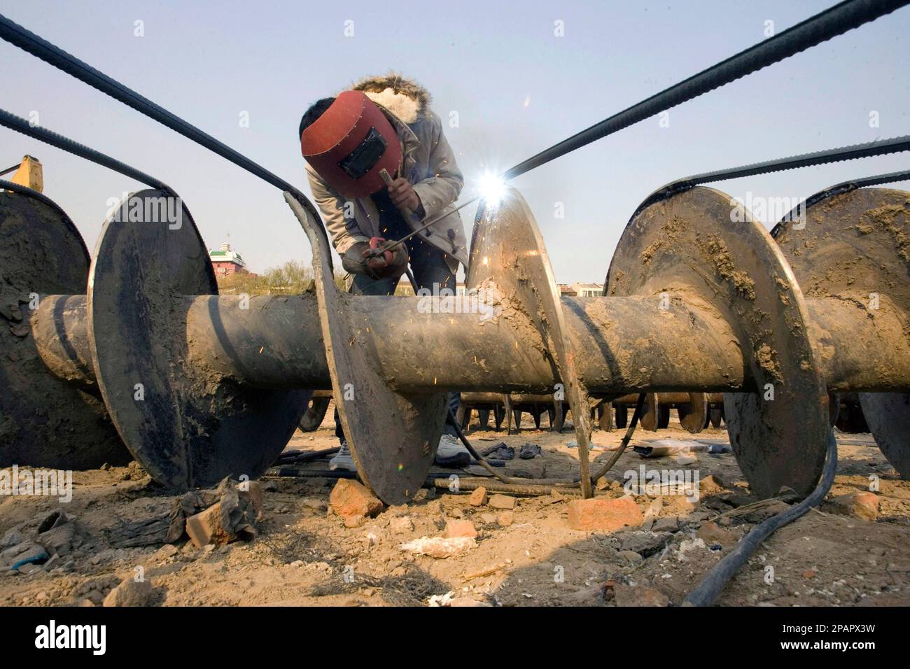 A Chinese worker performs welding work on steel rods using a steel ...