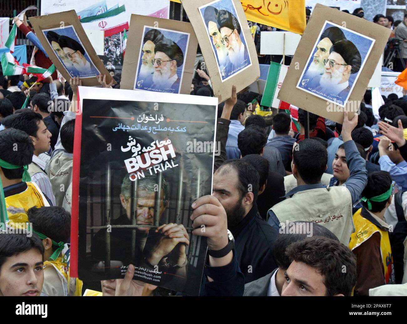 Holding an anti-Bush poster and pictures of Iranian late revolutionary ...