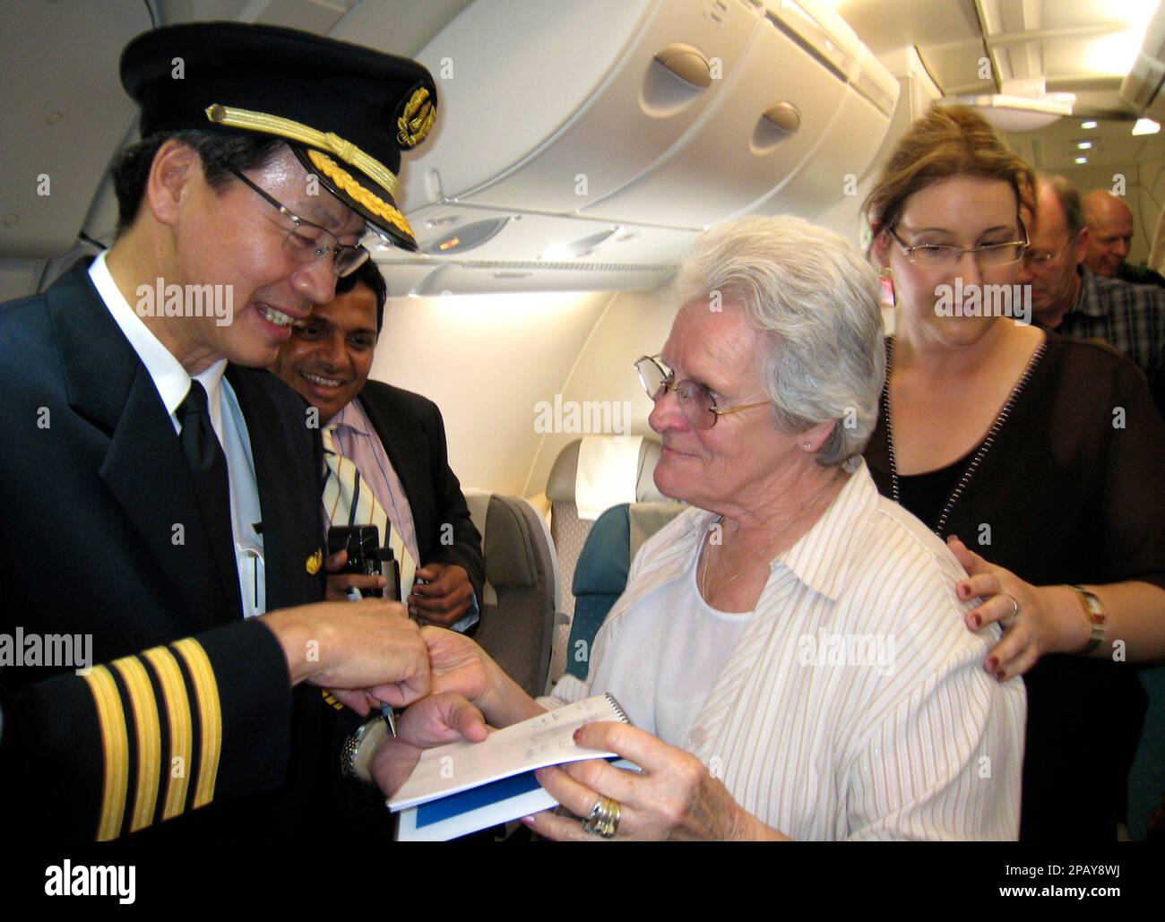 An unidentified elderly woman asks Captain Robert Ting, left, for his ...