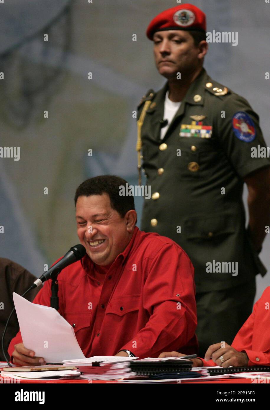 Venezuela's President Hugo Chavez laughs as a soldier stands behind in ...
