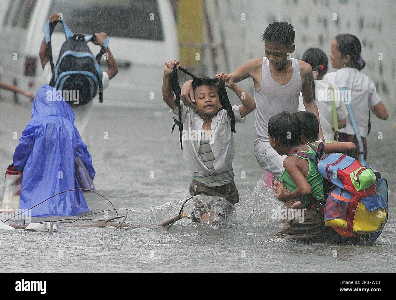 A Filipino student is assisted as he wades through floods as they walk outside their school in ...