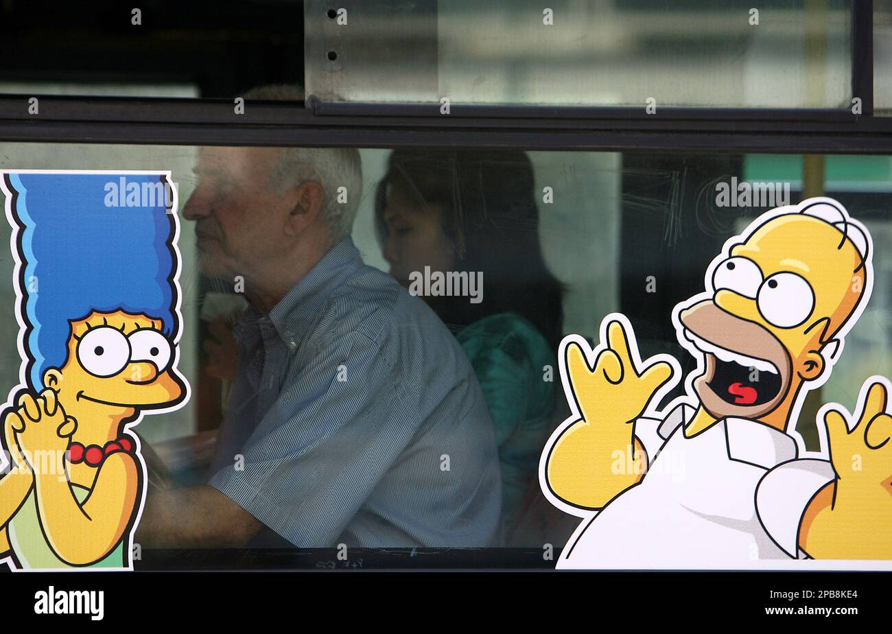 Passengers are seen behind an advertising banner on the window of a bus ...