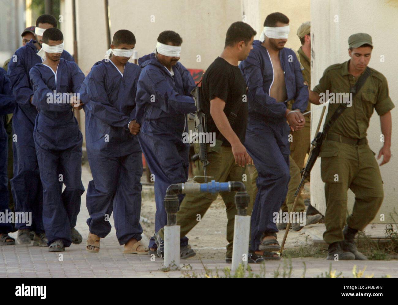 Israeli soldiers lead a group of blindfolded and handcuffed ...