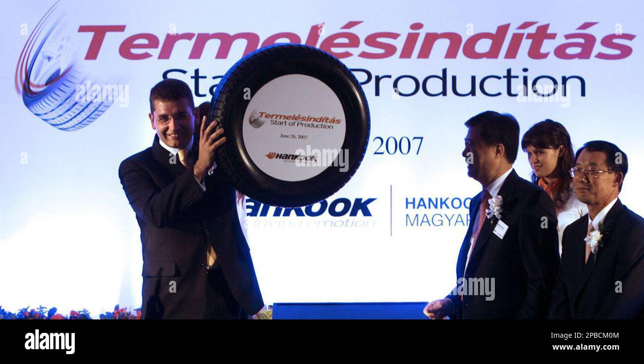 Hungarian Minister of Economics Janos Koka, left, lifts the first tyre ...