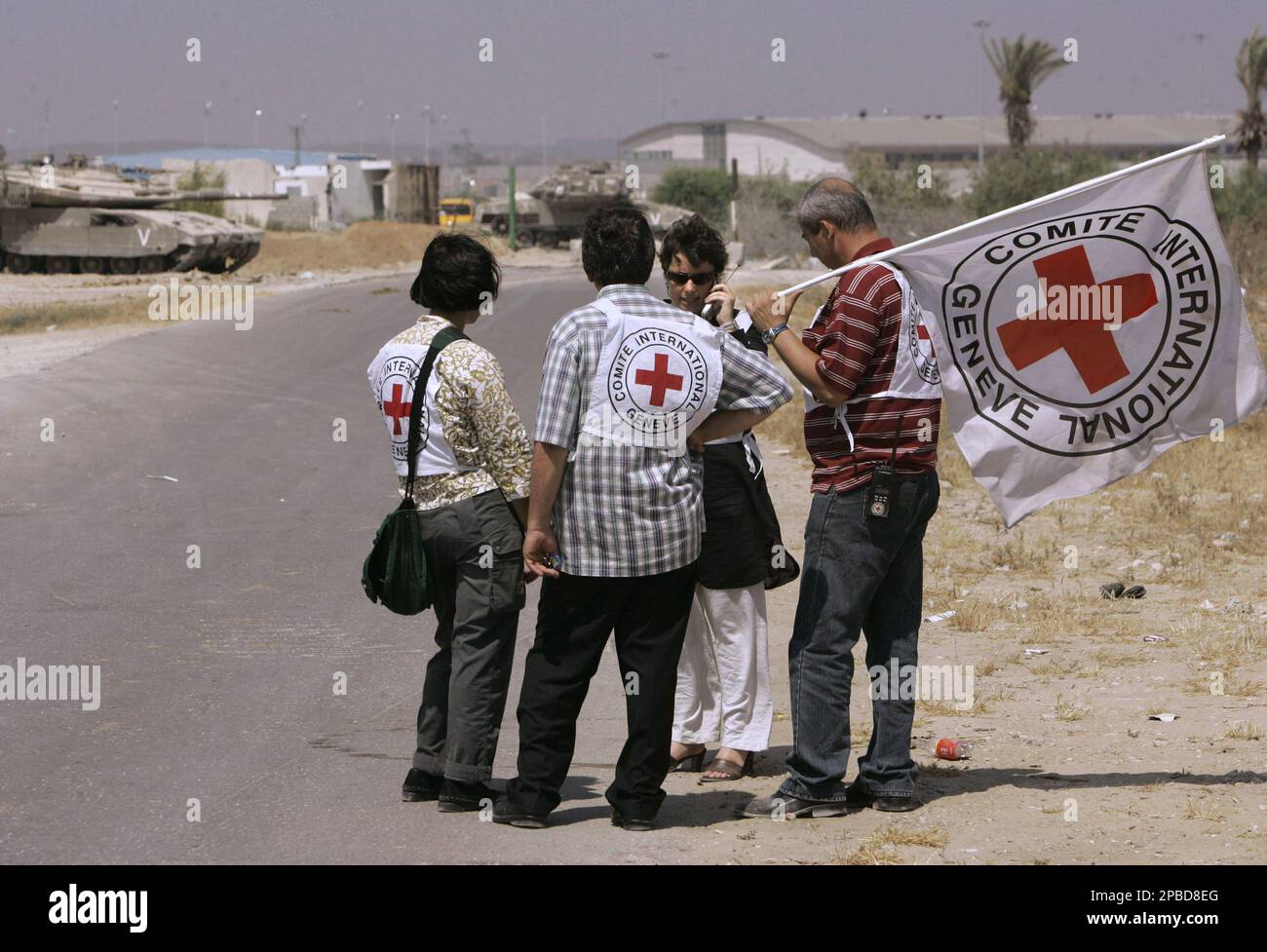 Workers from the Red Cross stand on the road as Israeli tanks are seen ...
