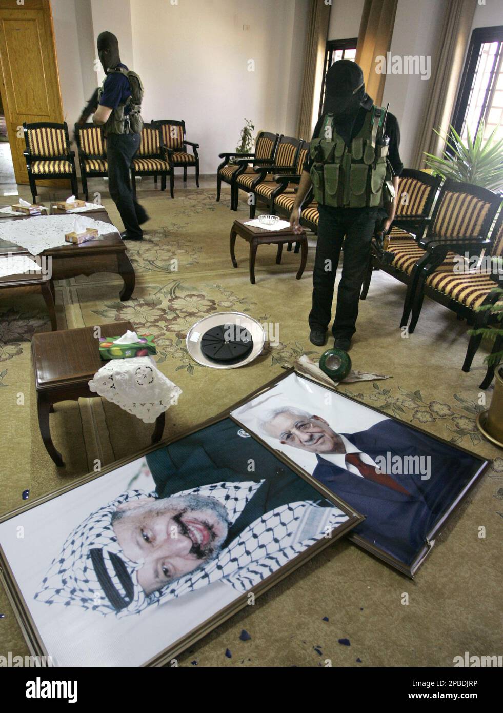Palestinian militants from Hamas stand over pictures of Palestinian ...