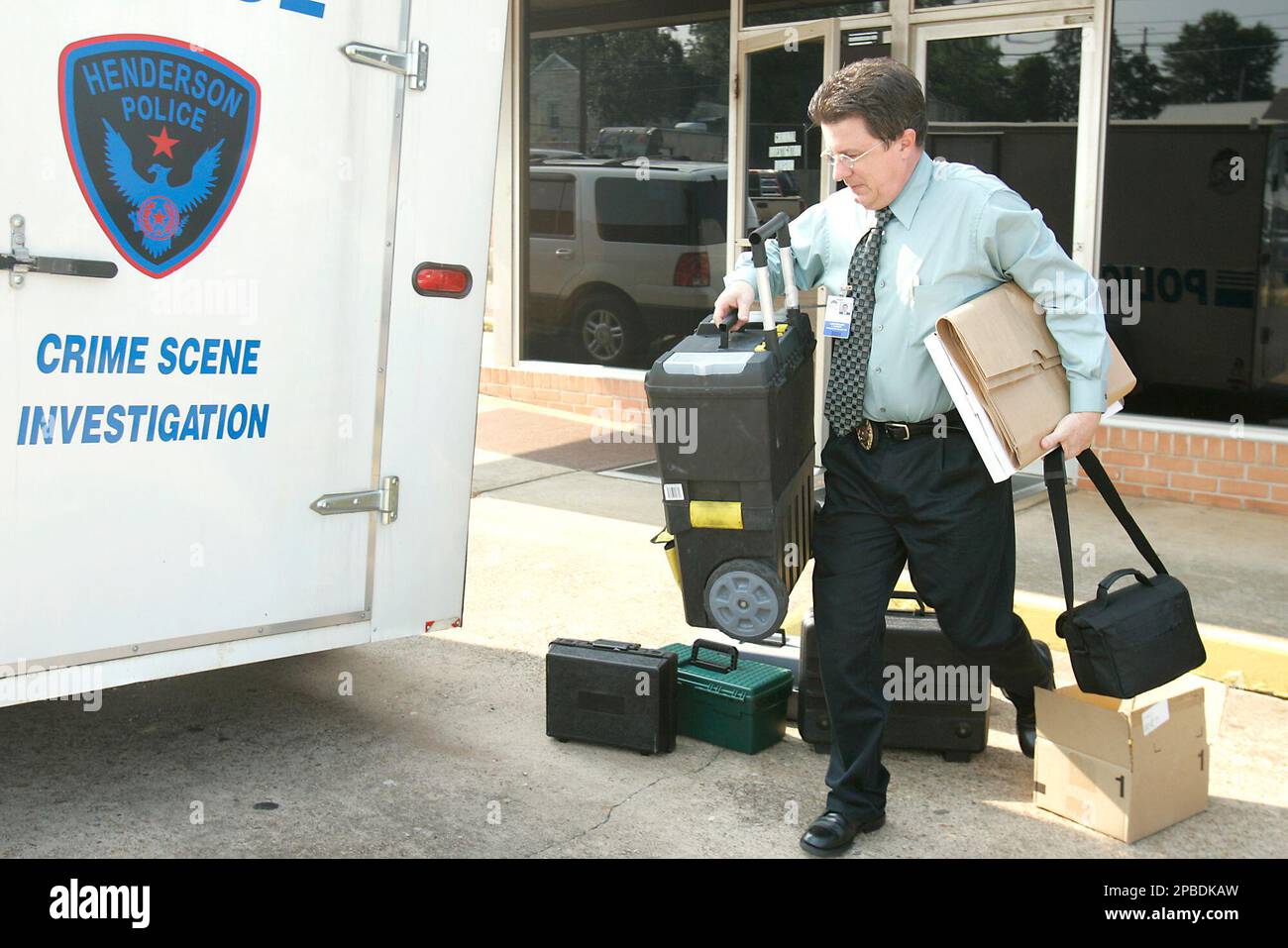 Henderson, Texas, police officer Craig Sweeney carries evidence from the offices of the Rusk ...