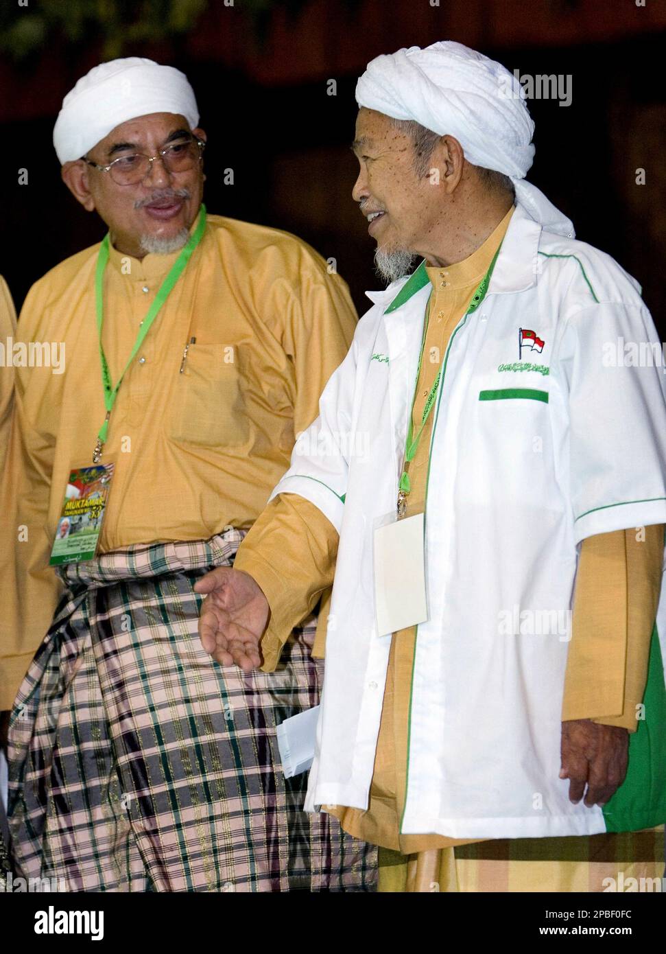Opposition spiritual leader Nik Aziz Nik Mat, right, shares a light ...