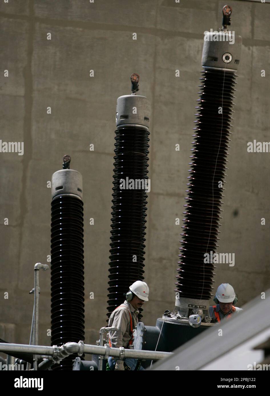 Electrical workers install new bushings for a new transformer at the ...