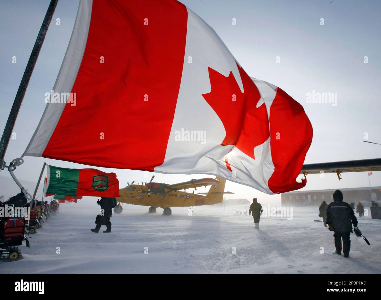 A Canadian flag flies from a snowmobile as military personnel gather ...