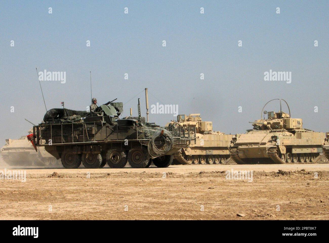 A Stryker armored vehicle passes parked Bradley fighting vehicles as it ...