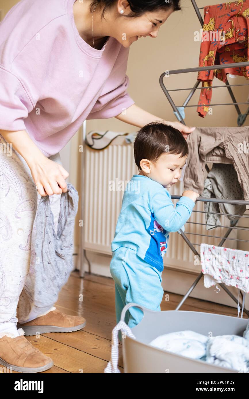 Vertikales Foto einer neuen mutter, die versucht, Wäsche und nasse ...