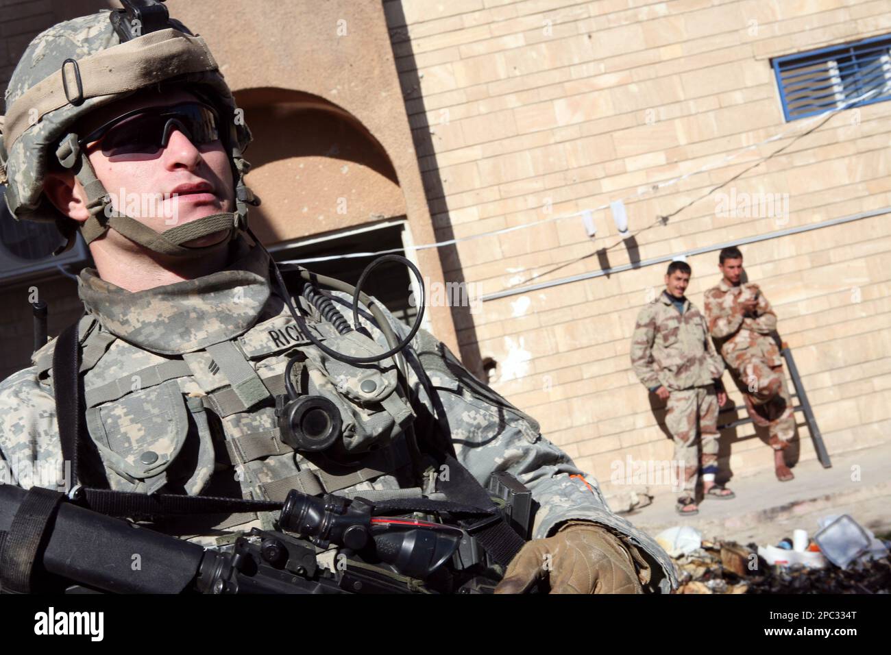 Sergeant Justin Richey from Palestine, Tx, is watched by Iraqi soldiers ...