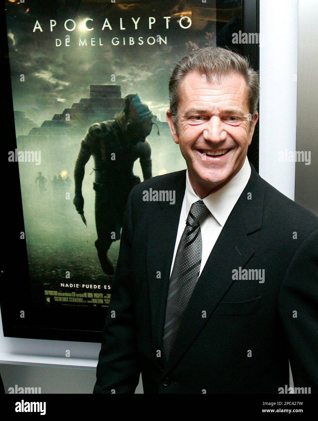 Mel Gibson walks past a poster for his new movie, "Apocalypto," during ...
